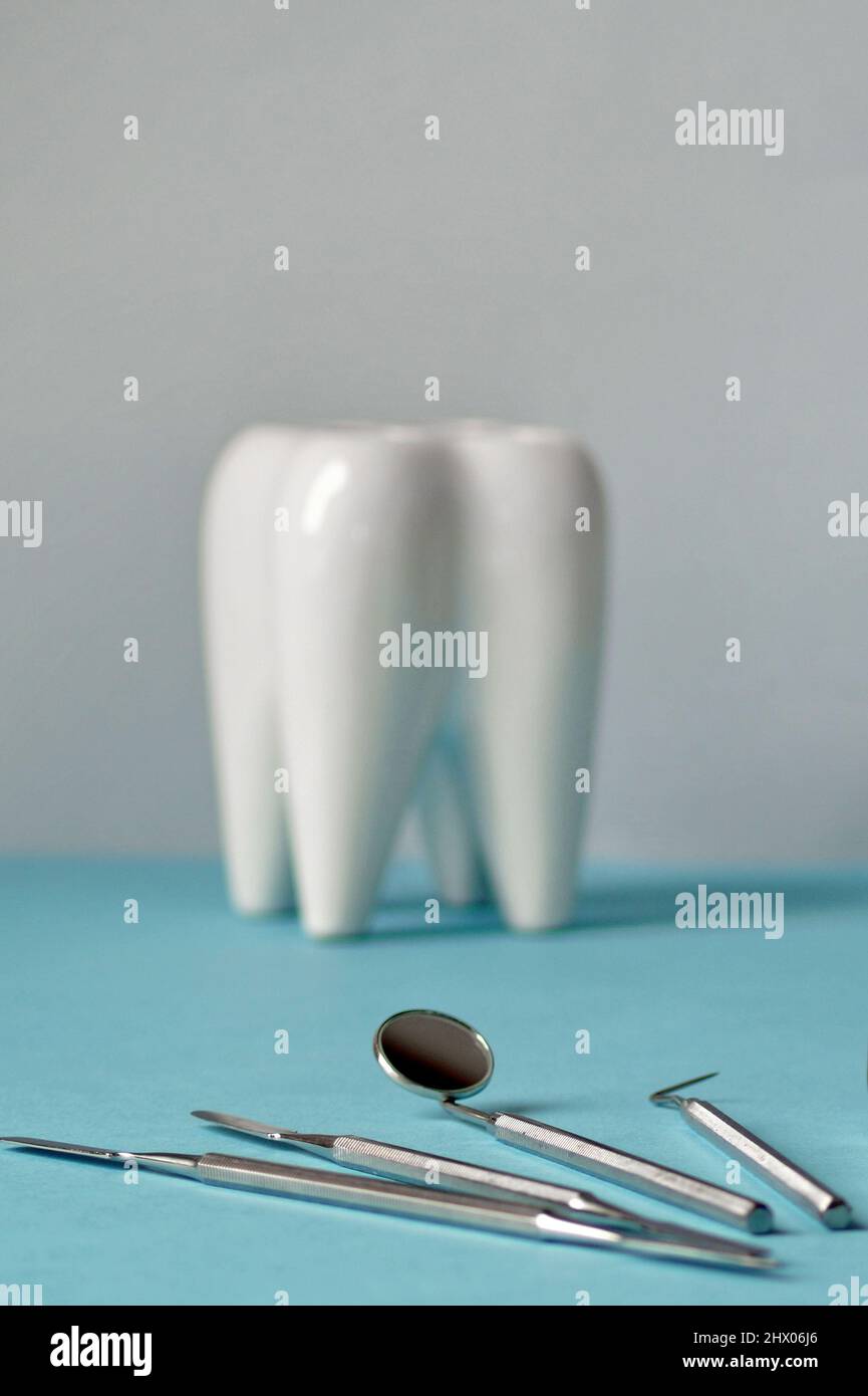 on the table in front of a beautiful white tooth lie the dentist's ...