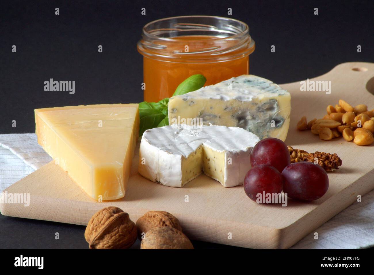 Three types of cheese, a jar of delicious honey, nuts, grapes and basil ...