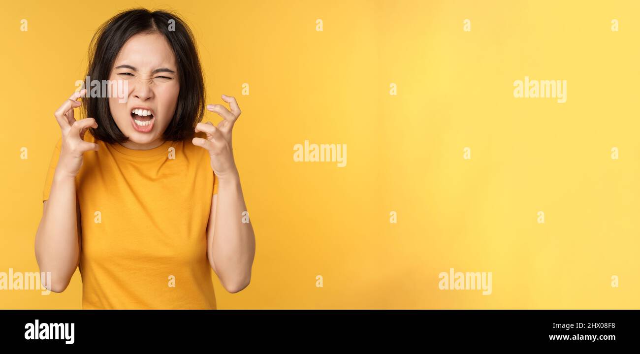 Image of angry asian woman, shouting and cursing, looking outraged ...