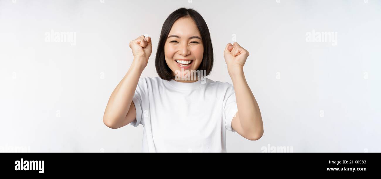 Portrait of enthusiastic asian woman winning, celebrating and ...