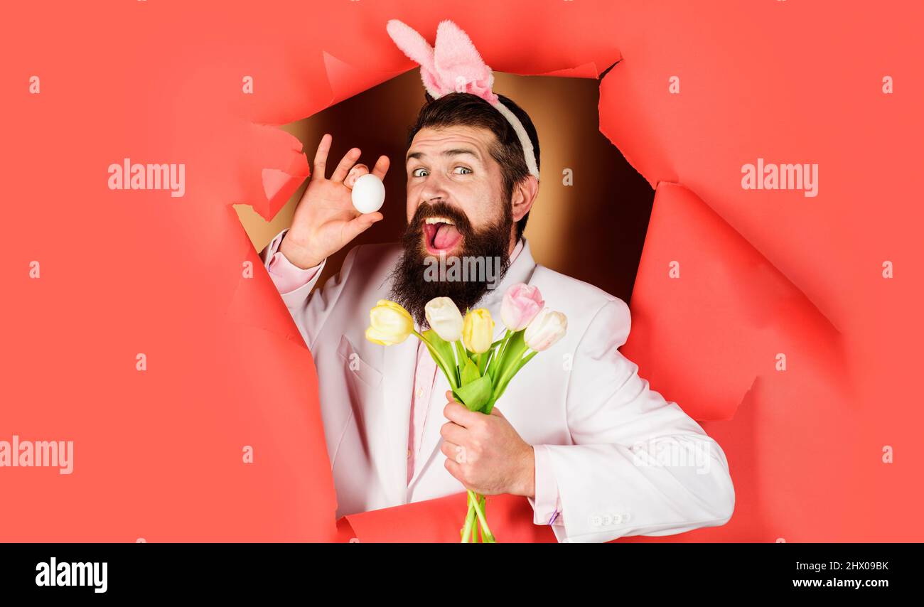 Easter Day. Happy bearded man with easter egg and flowers. Rabbit guy ...