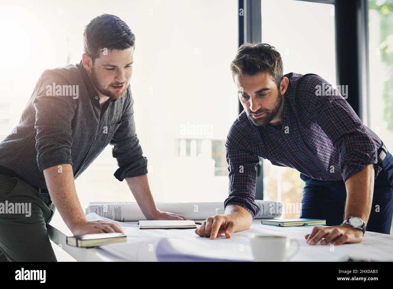 They are a two man team. Shot of two young businessmen working through ...