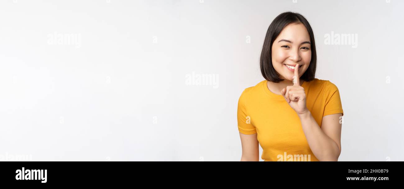 Keep quiet. Cute asian woman make shhh gest, showing shush, hush sign ...