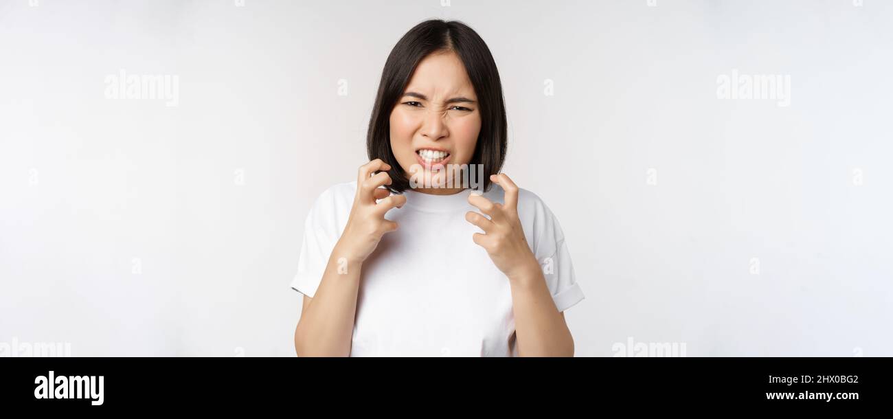 Angry asian woman cursing, looking outraged and annoyed, clench teeth ...