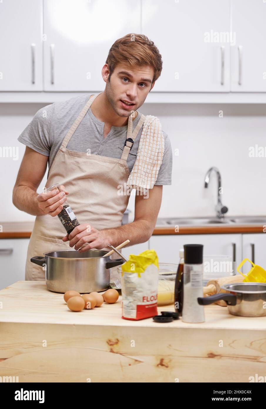 Season to taste. Cropped shot of a handsome young man cooking in the ...