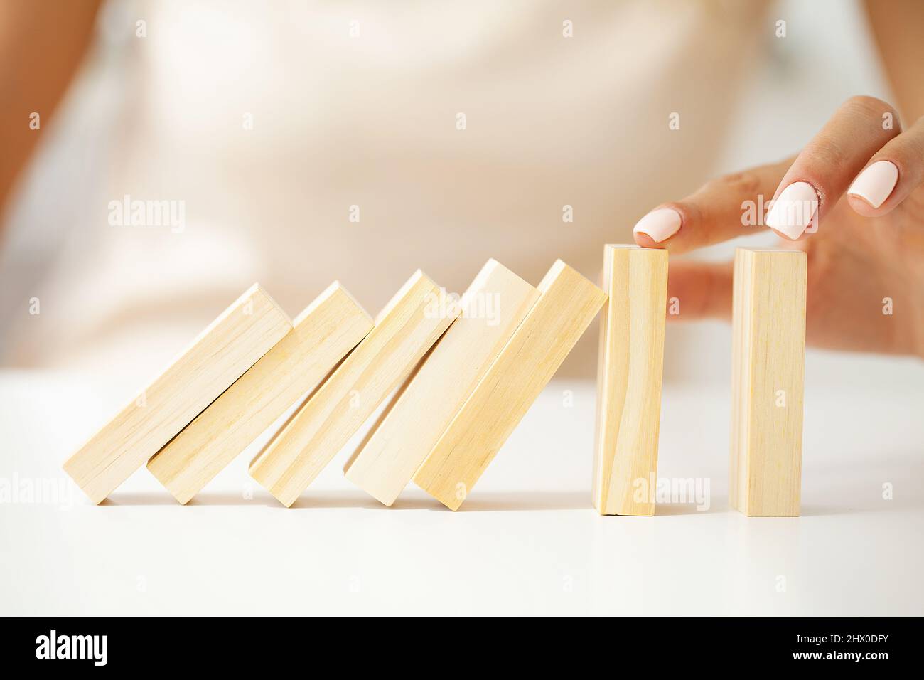 Hand of woman stopping and protect wooden block falling Stock Photo - Alamy