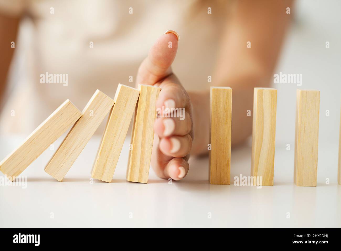 Hand of woman stopping and protect wooden block falling Stock Photo - Alamy