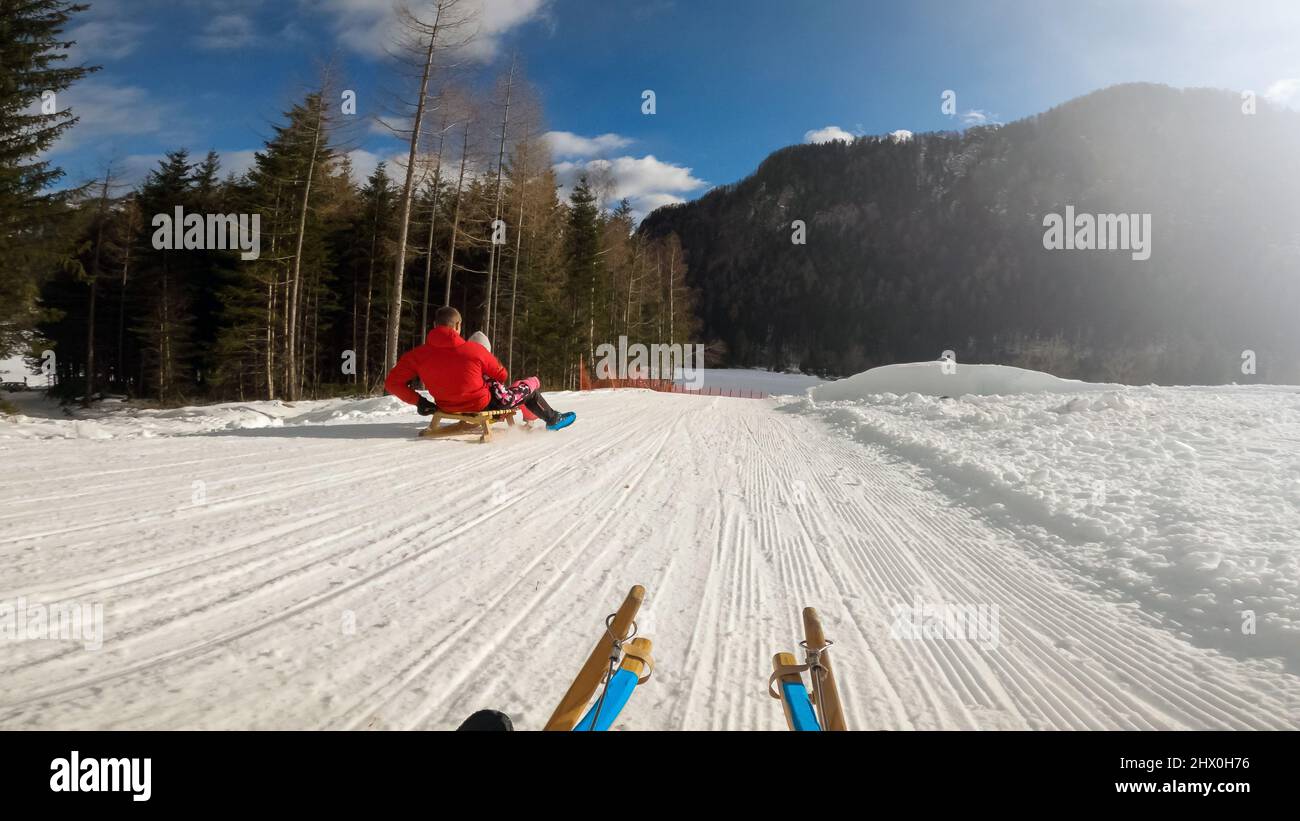Point of view of a child sledding with father and sister, riding a wood ...