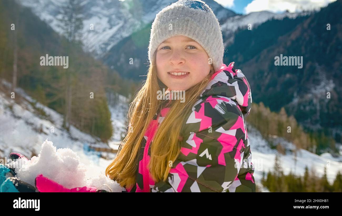 Pretty Caucasian girl in colorful snowsuit with knit hat and long hair ...