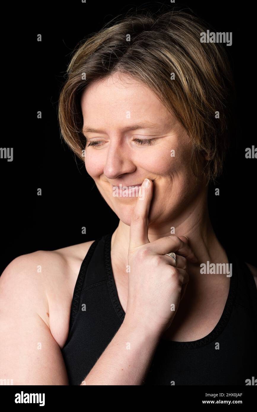 Low key studio portrait of a 35 year old white woman, playful thinking ...