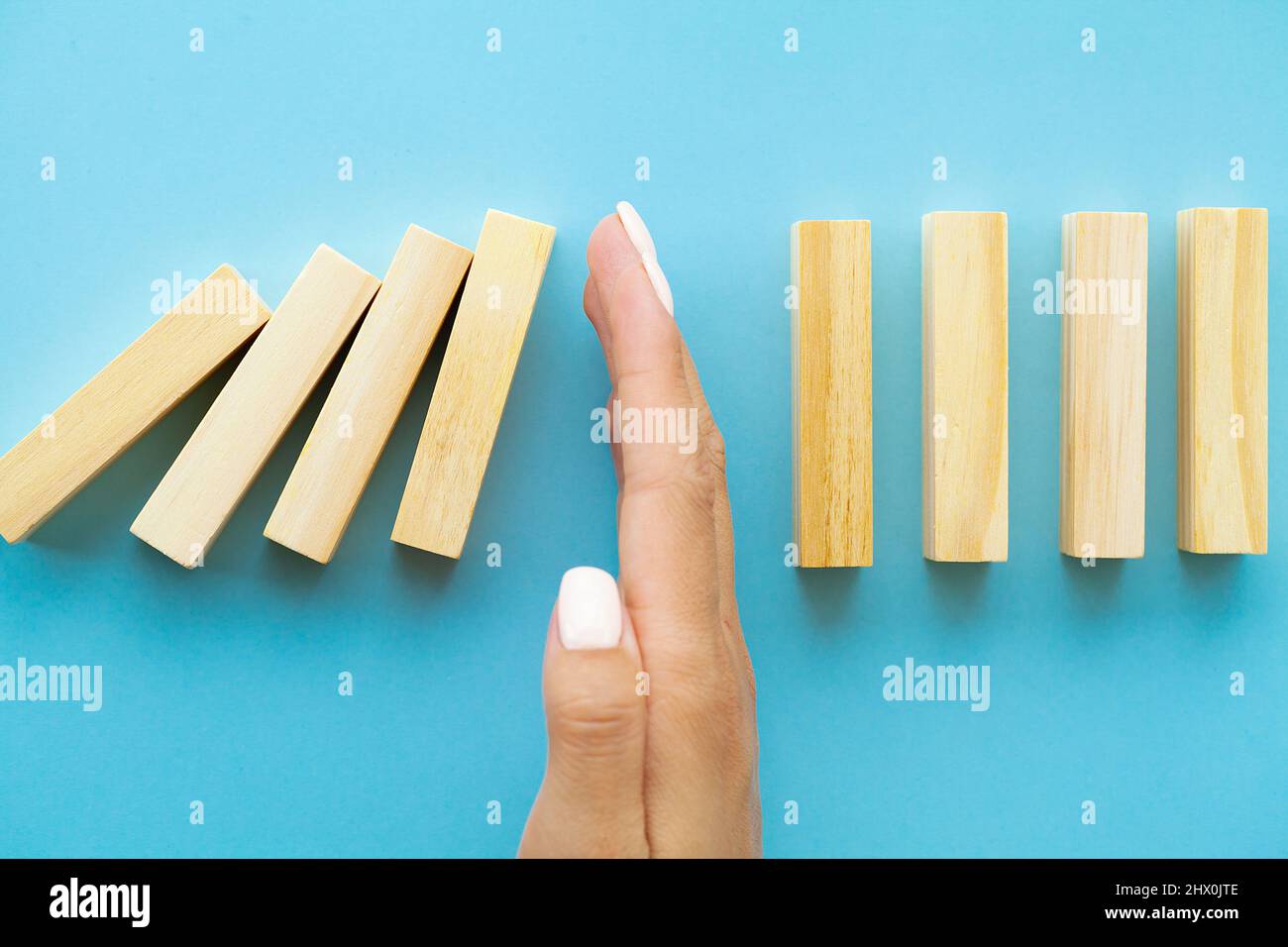 Hand of woman stopping and protect wooden block falling Stock Photo - Alamy