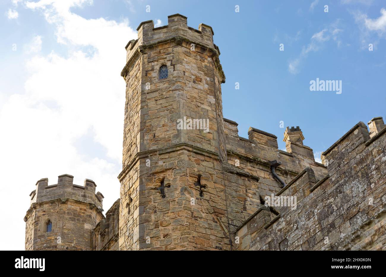 Looking upwards at the tower of a honey coloured castle building ...