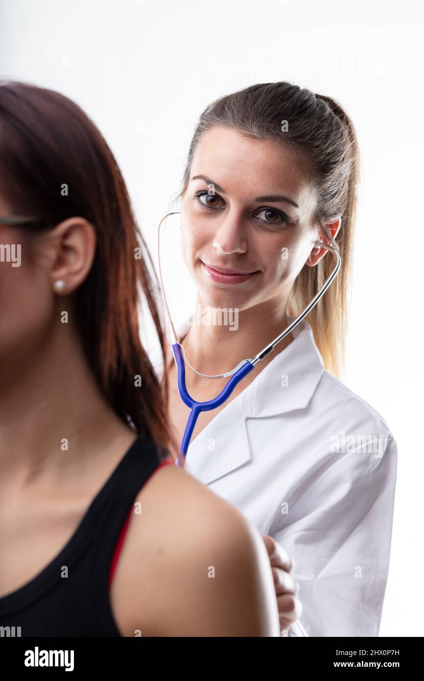 Doctor or cardiologist examining a female patient with a stethoscope in ...