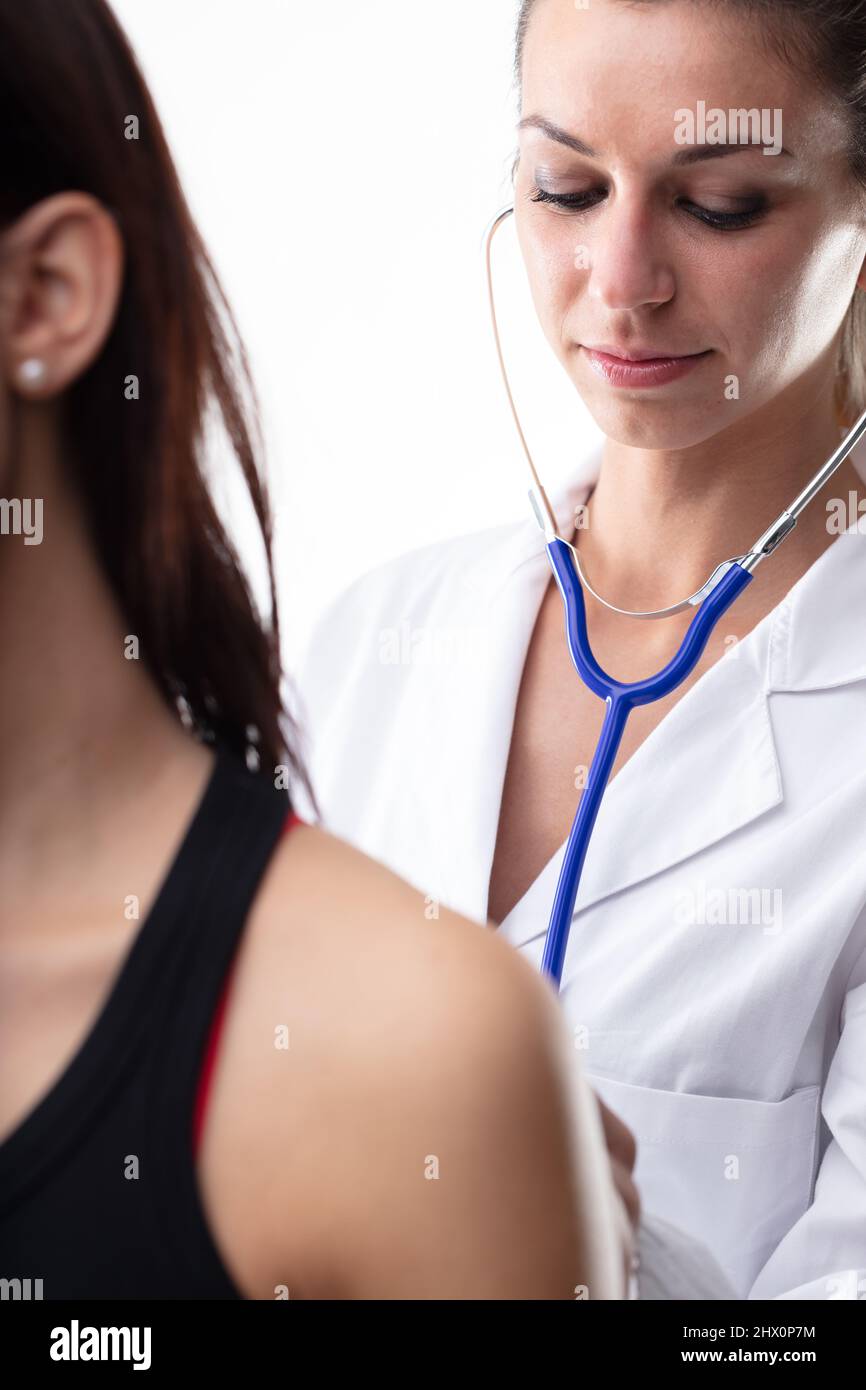 Doctor examining a female patient with a stethoscope listening to her ...