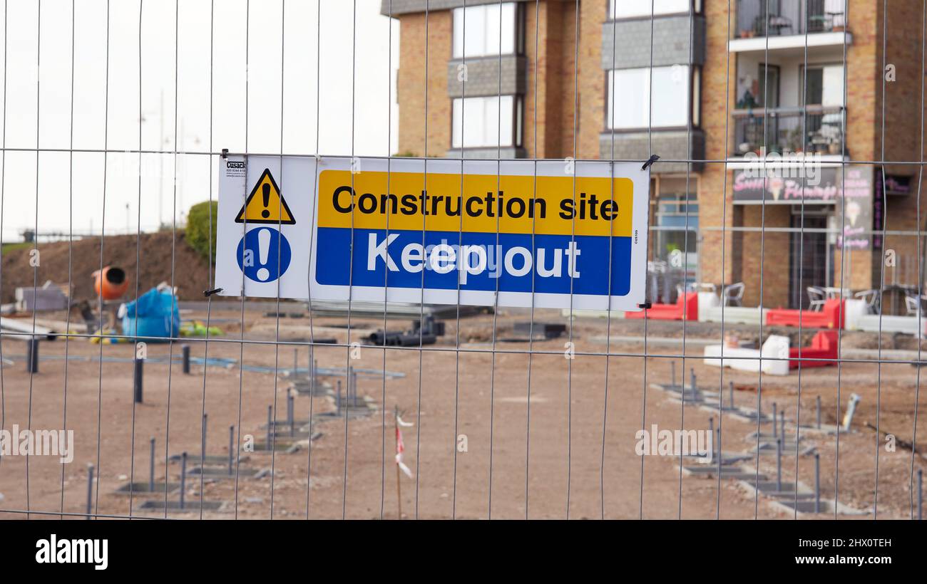 Keep out sign fitted against a see through fence around a building site ...