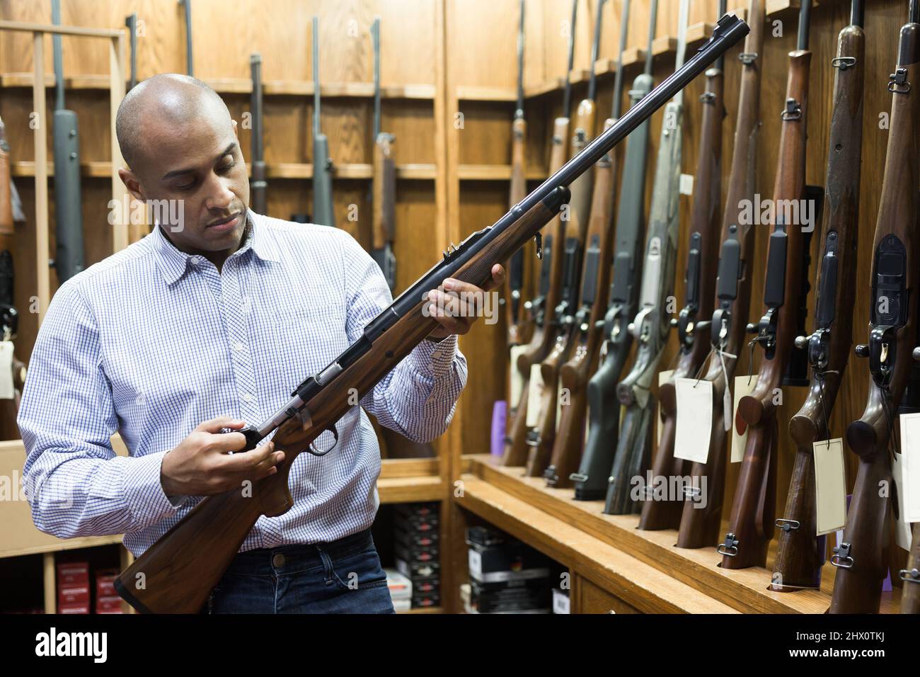Portrait of confident man in gun shop showing rifle Stock Photo - Alamy