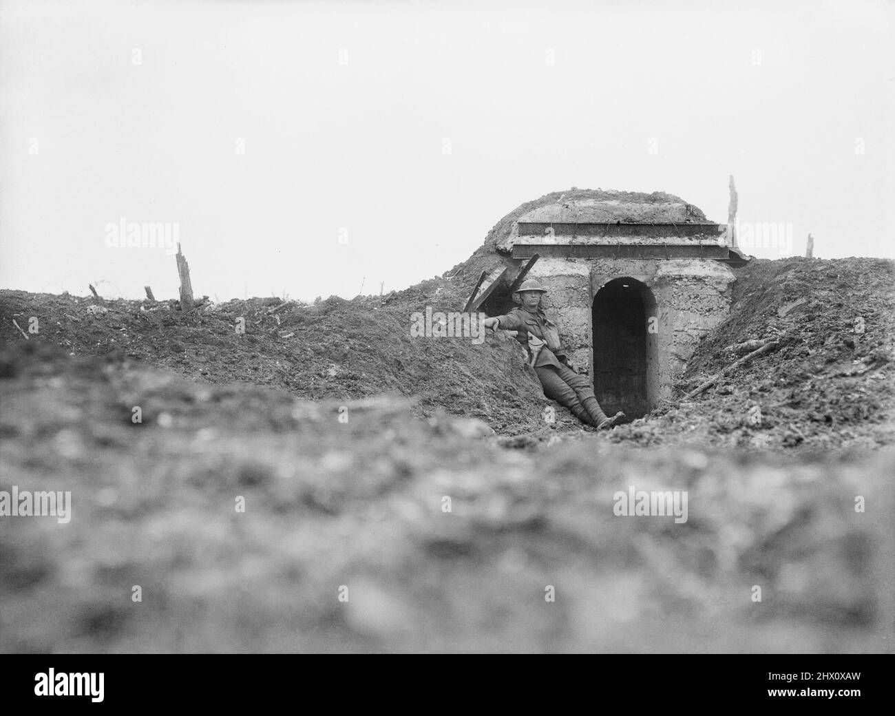 A British soldier sits by the entrance to a concrete pillbox in ruined ...