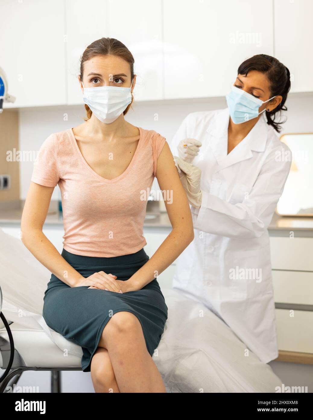 Confident female doctor making injection to woman Stock Photo - Alamy