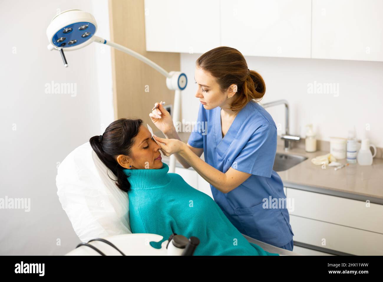 Beautician drawing correction lines on woman face Stock Photo - Alamy
