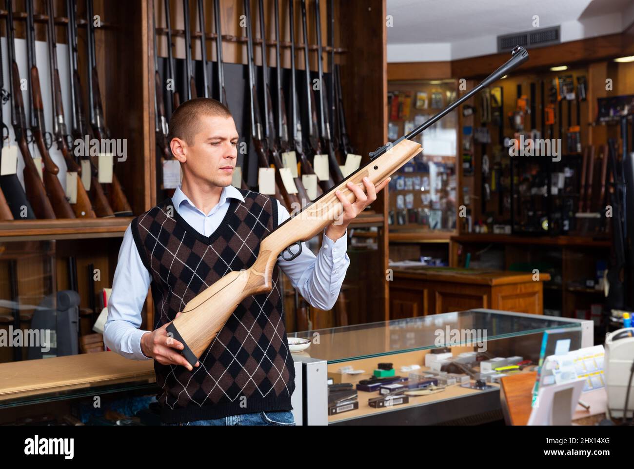 Gun shop salesman with air rifle in hand closeup Stock Photo - Alamy