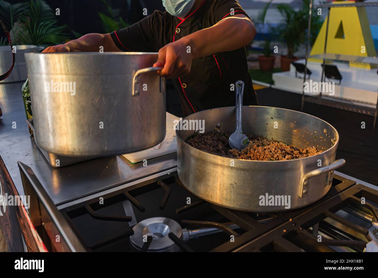 Cook arranges stainless steel pots as he prepares a large quantity food ...