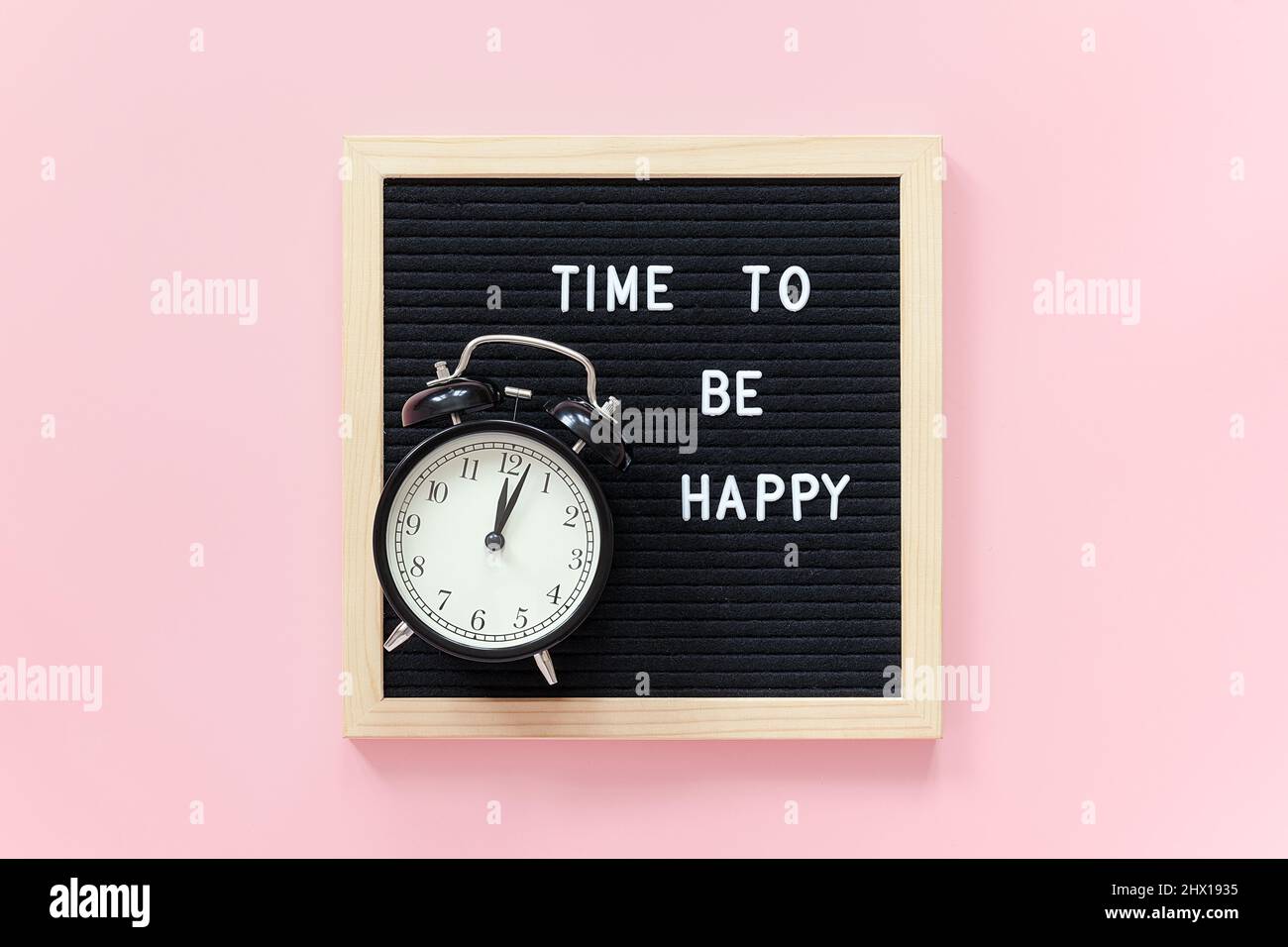 Time to be happy. Motivational quote on letterboard and black alarm ...