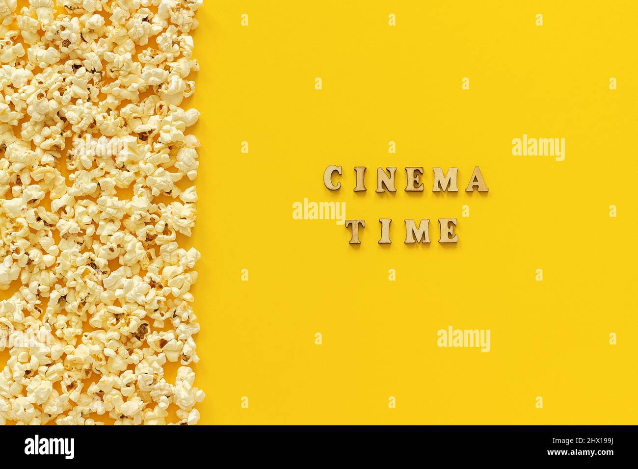 Scattered popcorn border left edge and cinema time on yellow paper ...