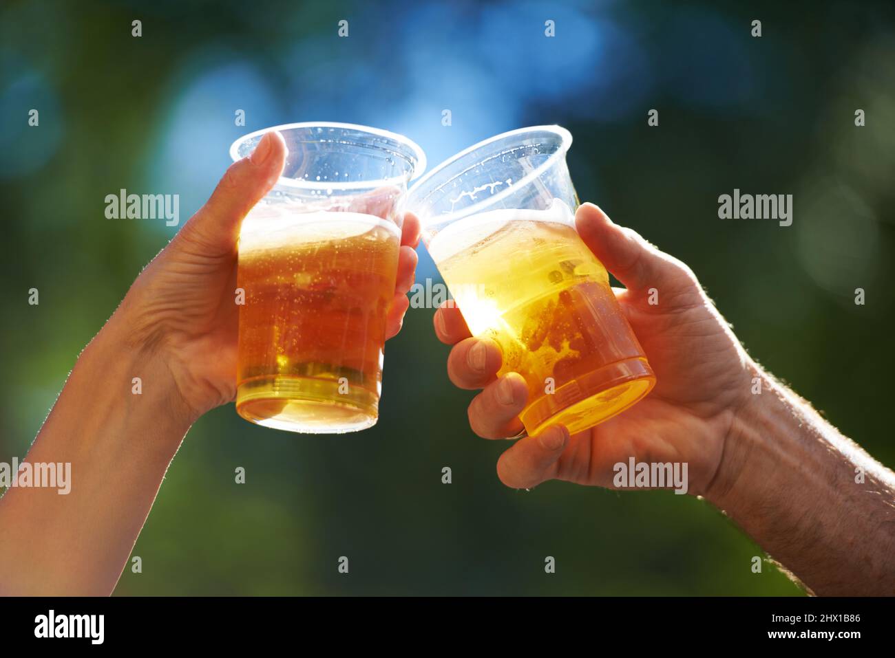 Enjoying a cold one. Cropped view of two people saying cheers with ...