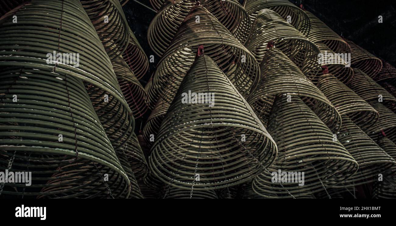Multiple large yellow incense coils hanging in stacks from the Ceiling ...