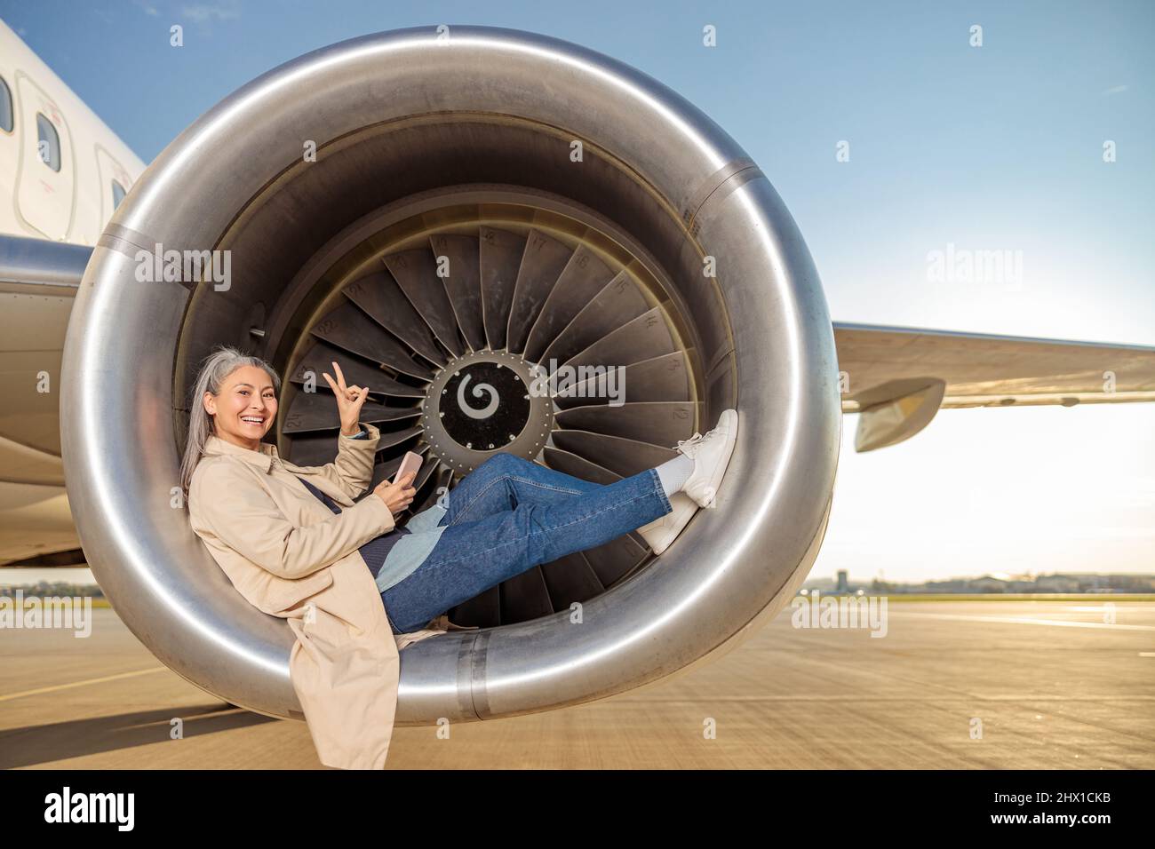 Joyful woman with smartphone lying in aircraft engine Stock Photo - Alamy