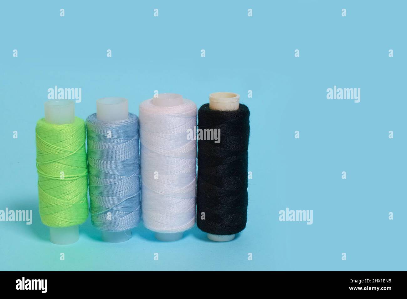 Coils with black, white, blue and green threads on a blue background ...