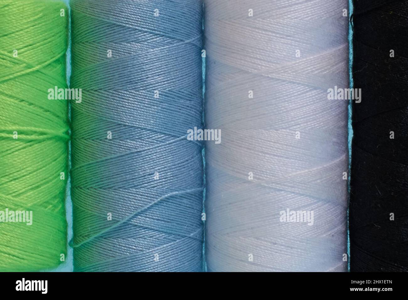 Coils with black, white, blue and green threads on a blue background ...