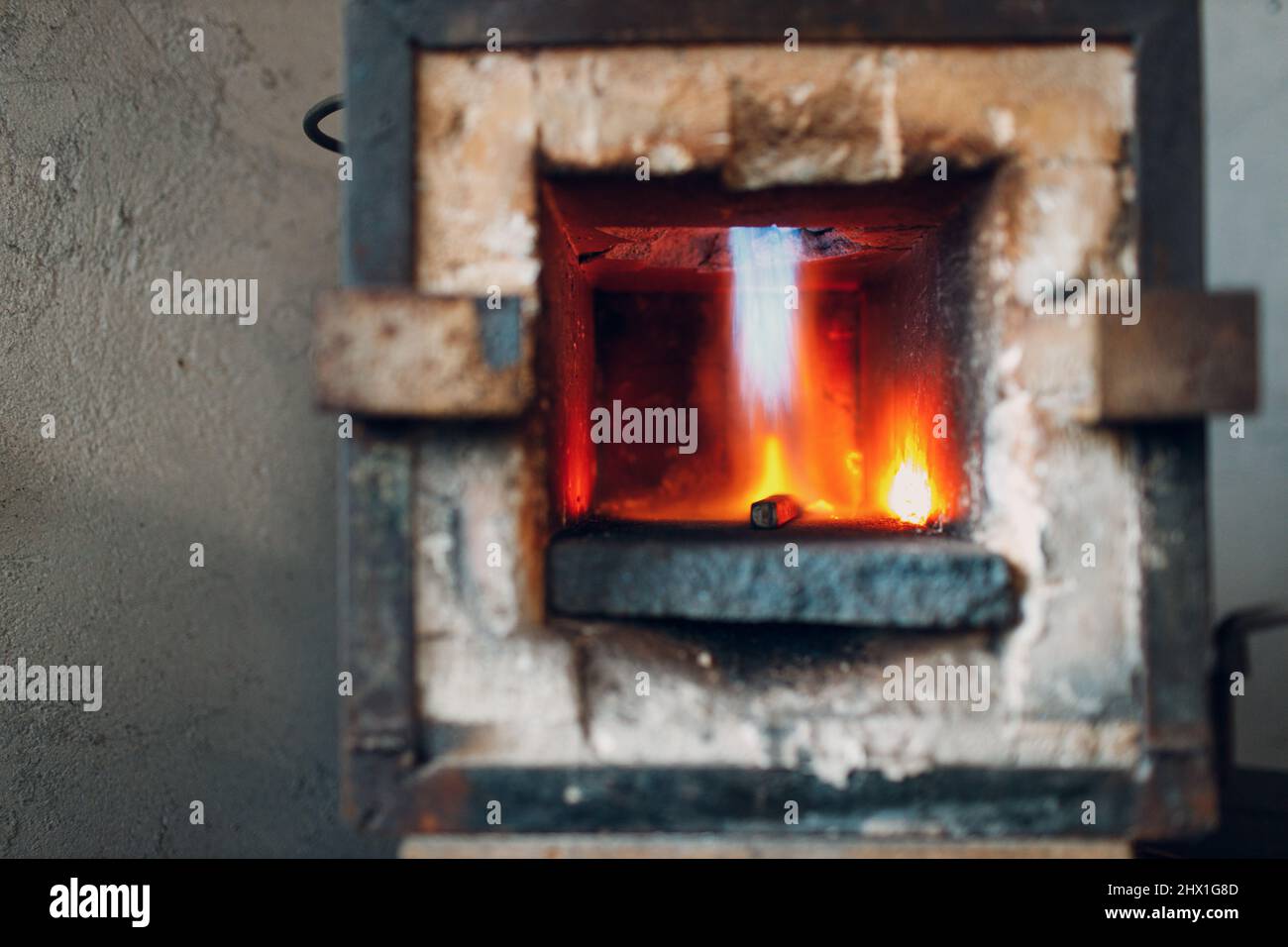 Blacksmith forge oven with hot flame. Smith heating iron piece of steel ...