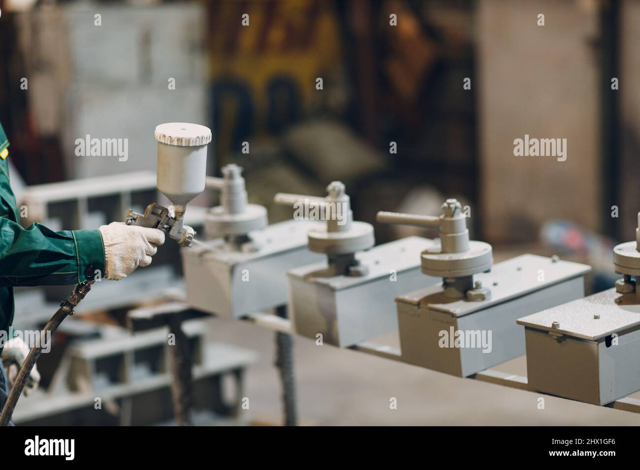 Powder primer coating of metal parts. Worker man in a protective suit ...