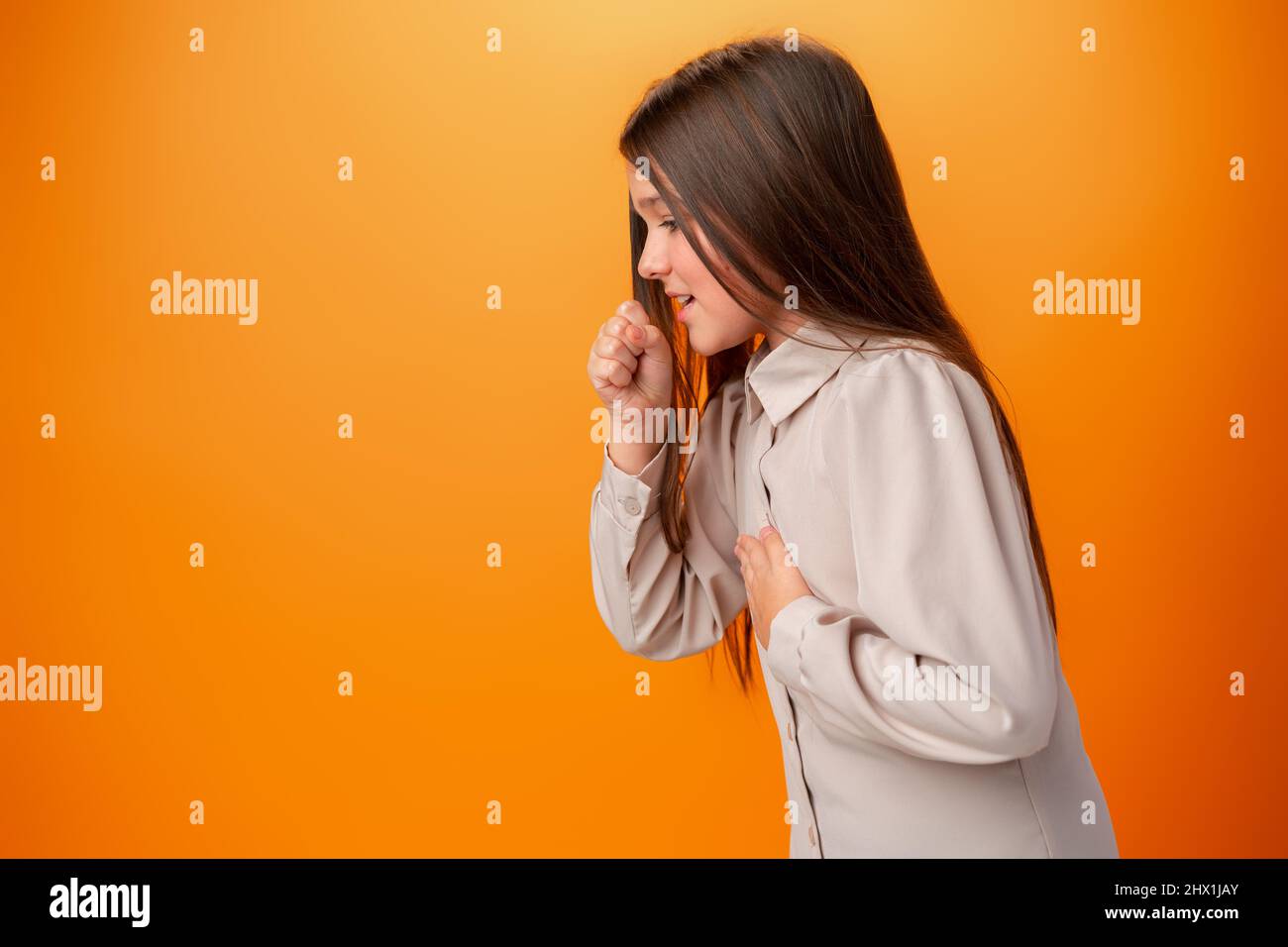 Teen girl wearing casual clothes feeling unwell and coughing against orange background Stock ...