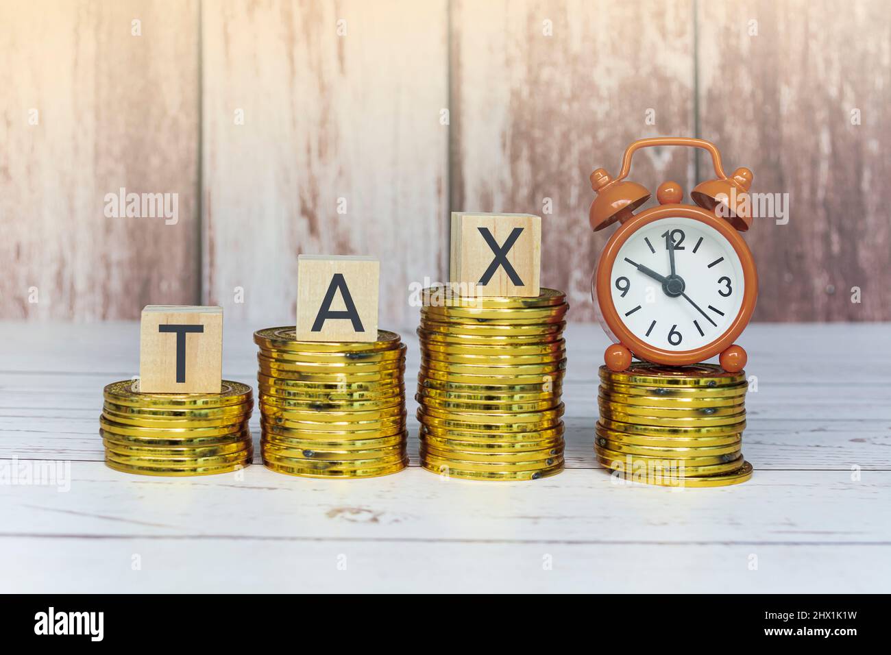 Tax text on wooden blocks and alarm clock set at 10 o'clock with gold ...