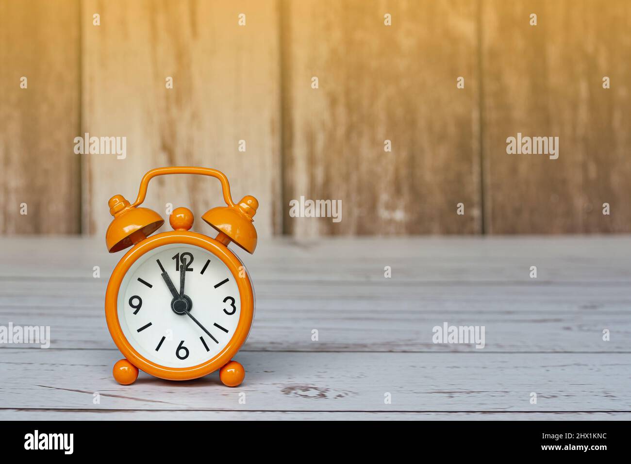 Orange alarm clock isolated on wooden desk. The clock set at 11 o'clock ...