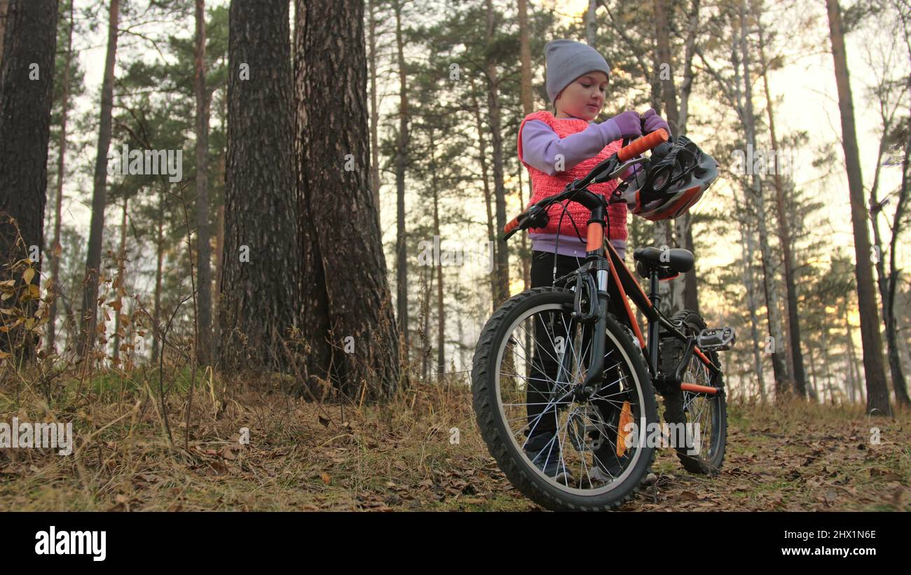 Kid wear helmet. One caucasian children rides bike road in autumn park ...