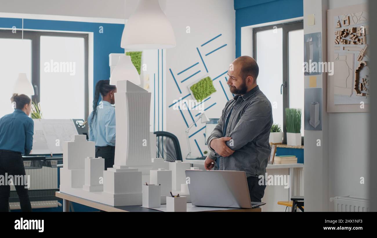 Man architect working with laptop and building model to design ...