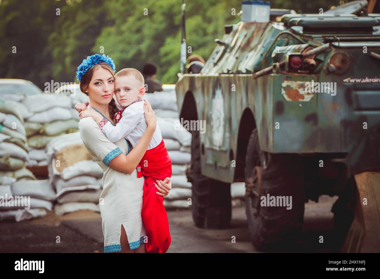 Young ukrainian woman stands with child boy on her arms in traditional ...