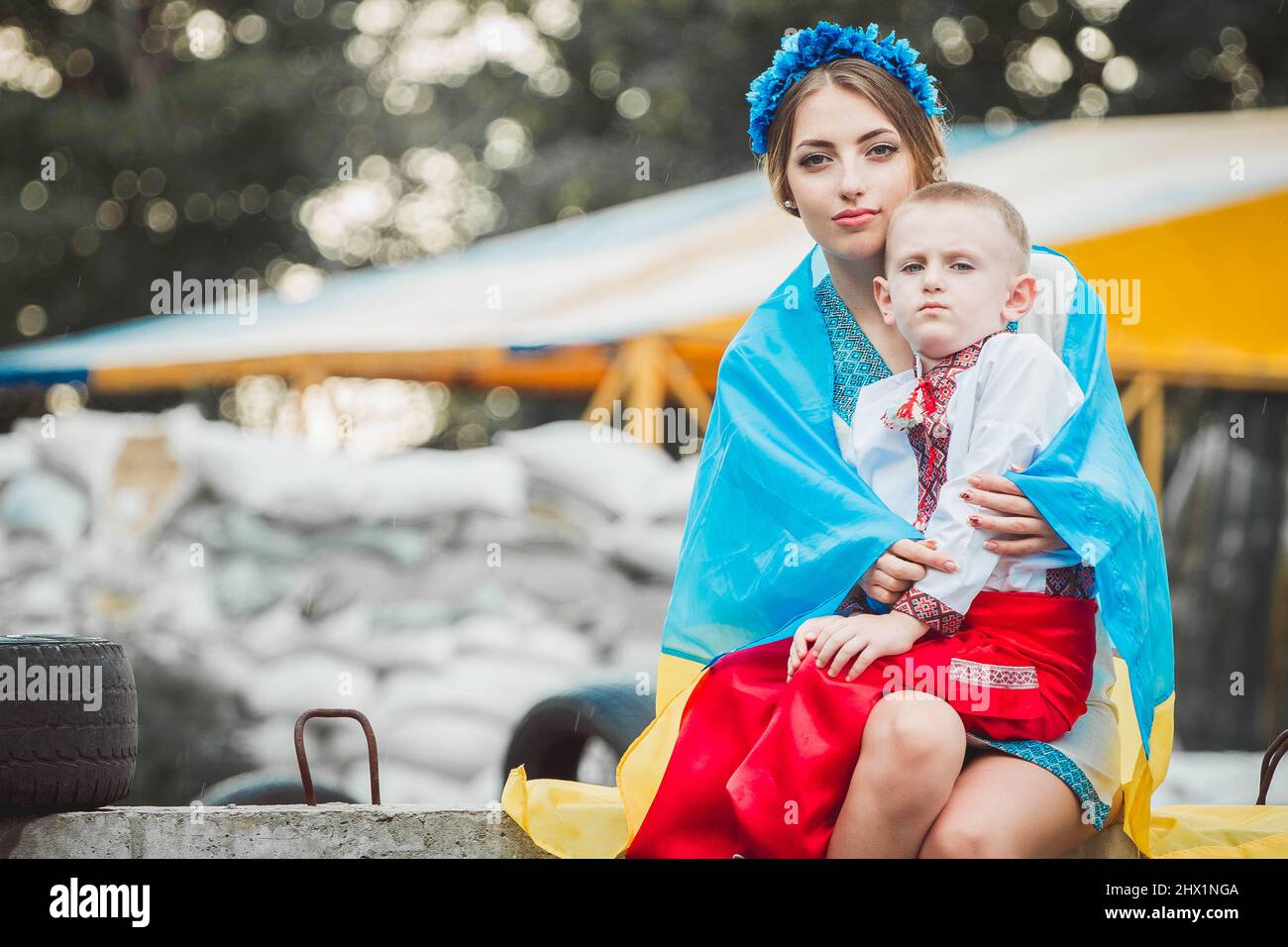 Young ukrainian woman wrapped in flag sits with child boy in ...
