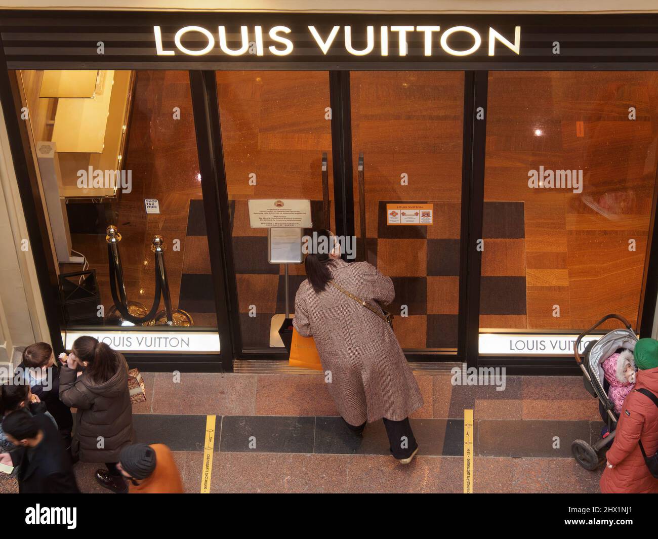 A woman looks through the glass doors of a closed Louis Vuitton ...