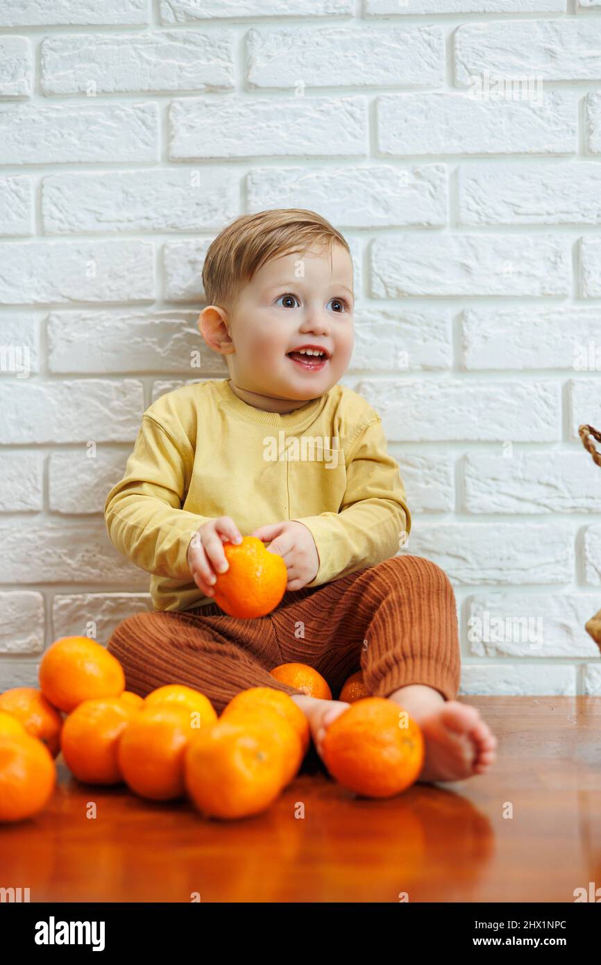 Little boy 2 years old eats tangerines. The kid wants to sit on citrus ...