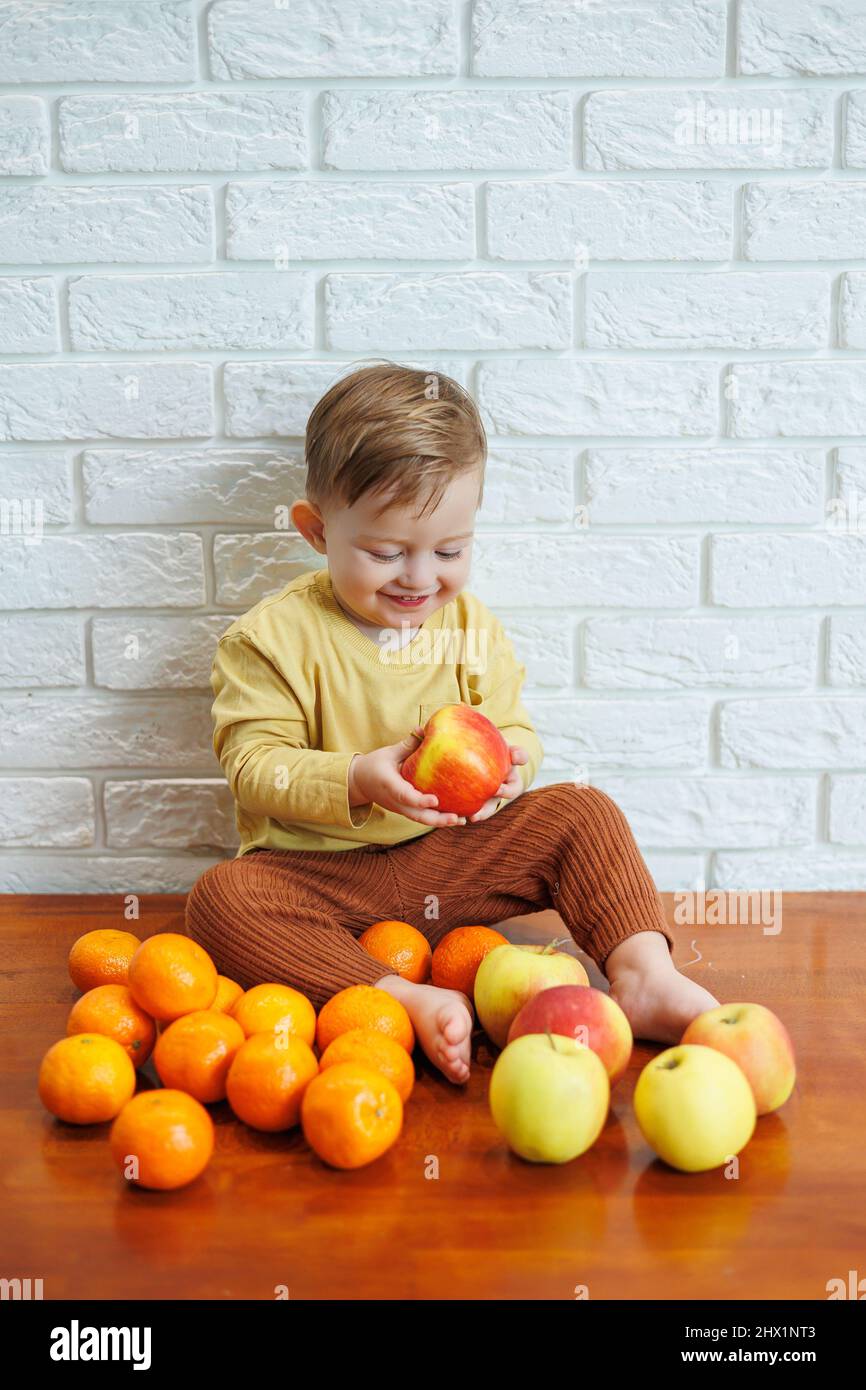 Cute smiling kid eating one fresh juicy red apple. Healthy fruits for ...
