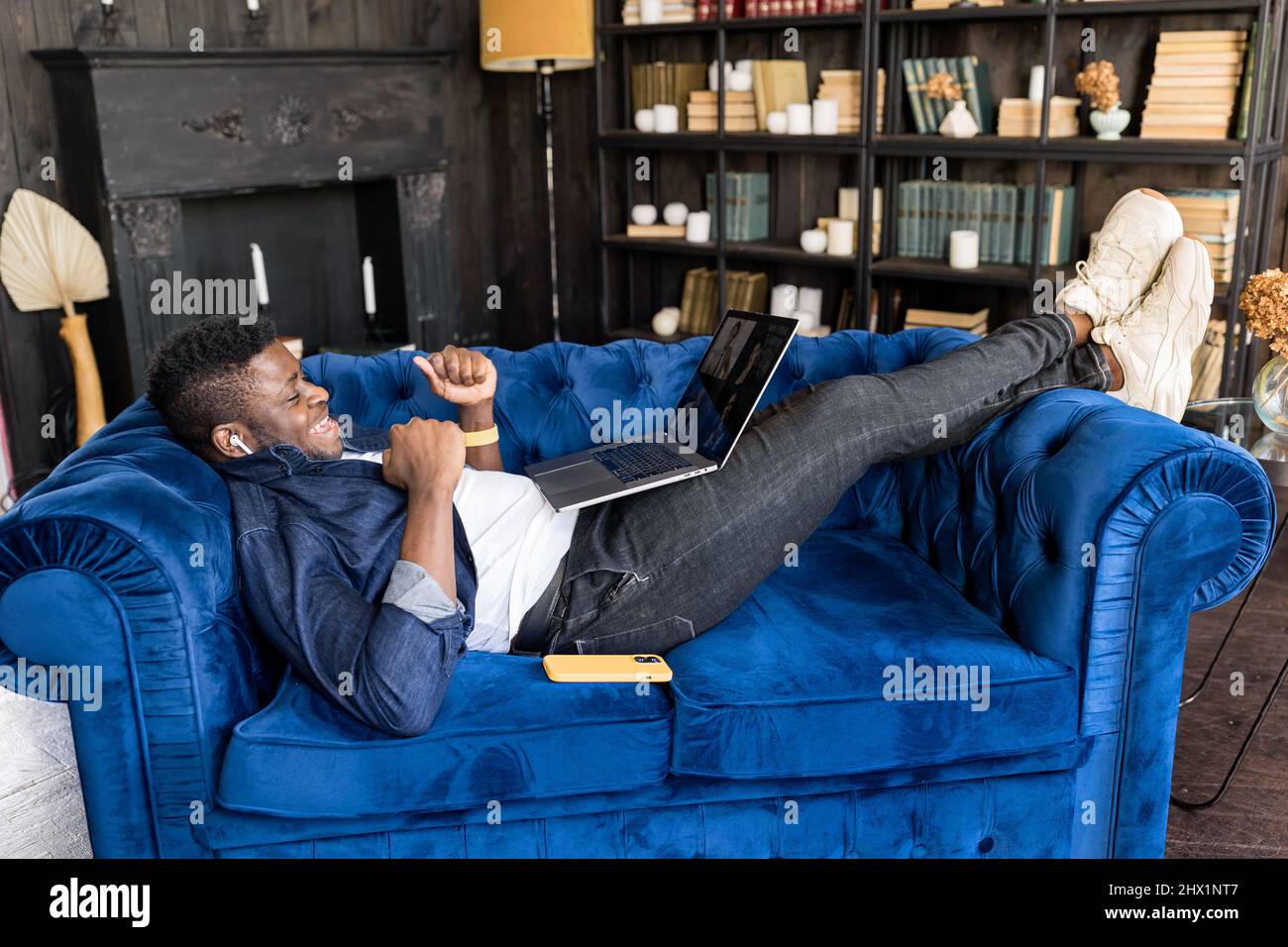 Satisfied African American male relaxing at sofa coach with laptop on ...