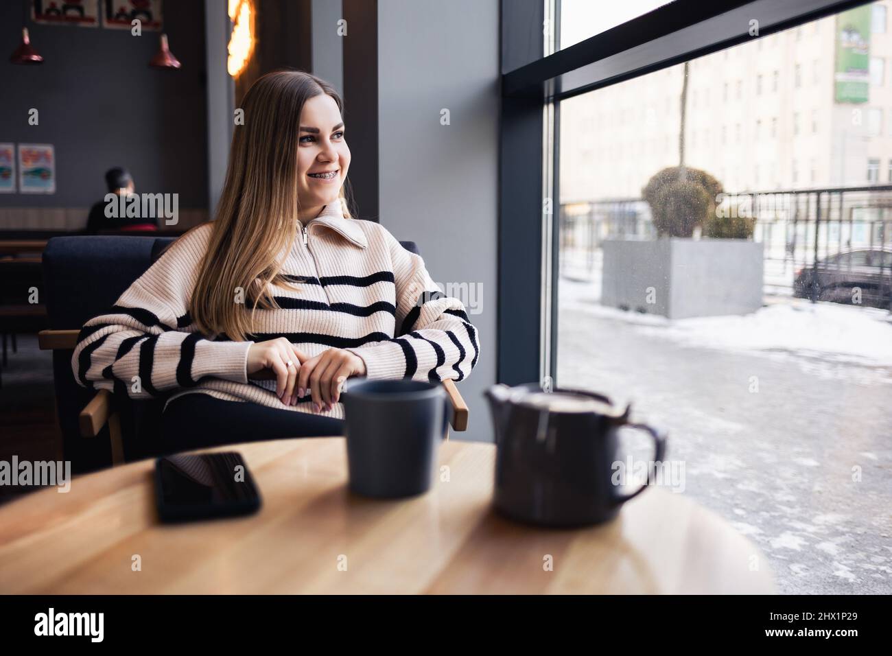 Beautiful smiling calm young woman drinking coffee looking out the ...