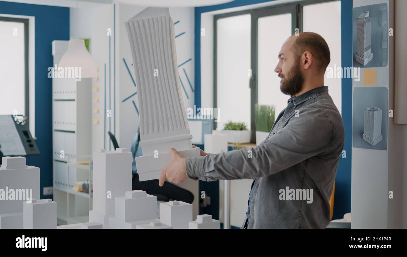 Man architect analyzing building model and maquette to design urban ...