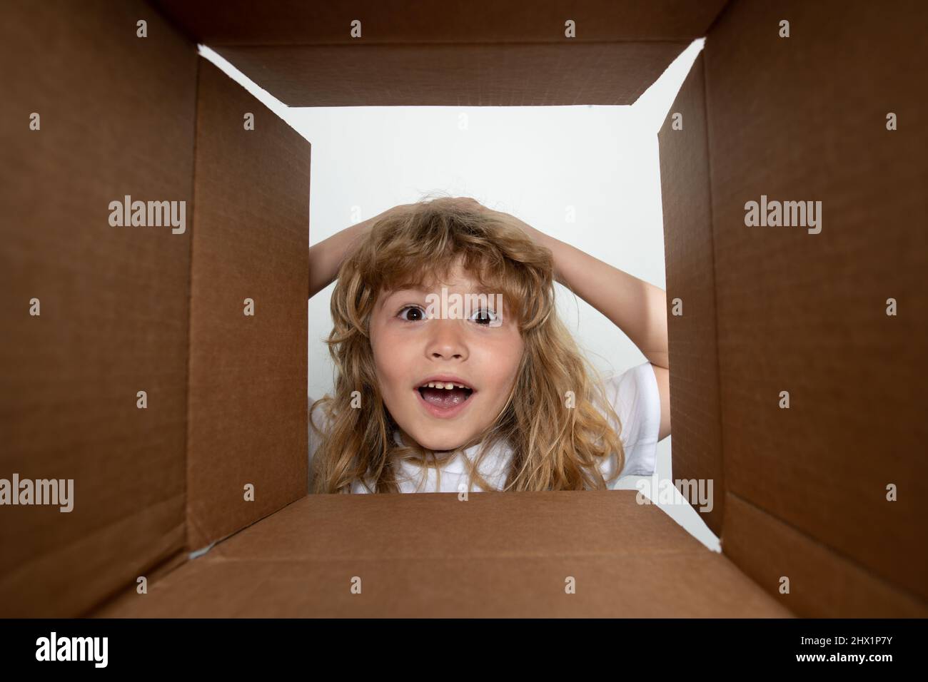 The surprised child unpacking, opening carton box and looking inside ...