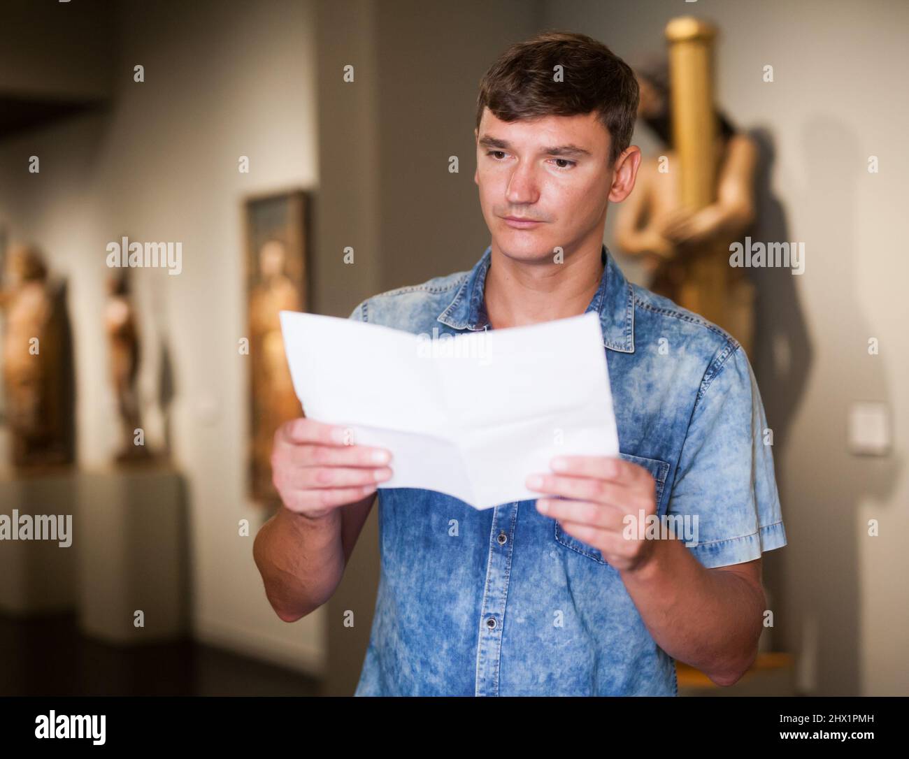 Man visiting museum with leaflet Stock Photo - Alamy
