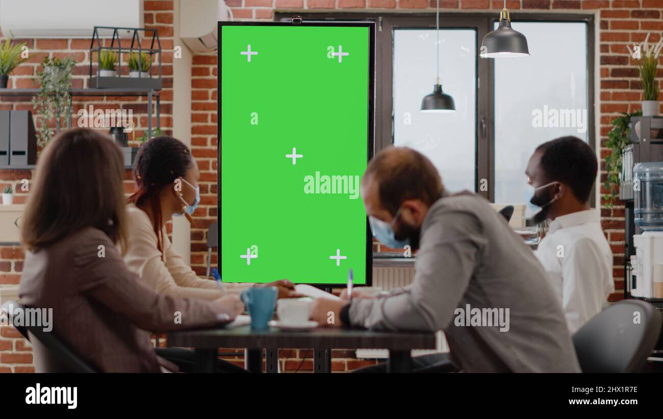 Team of diverse workmates working with vertically green screen on ...